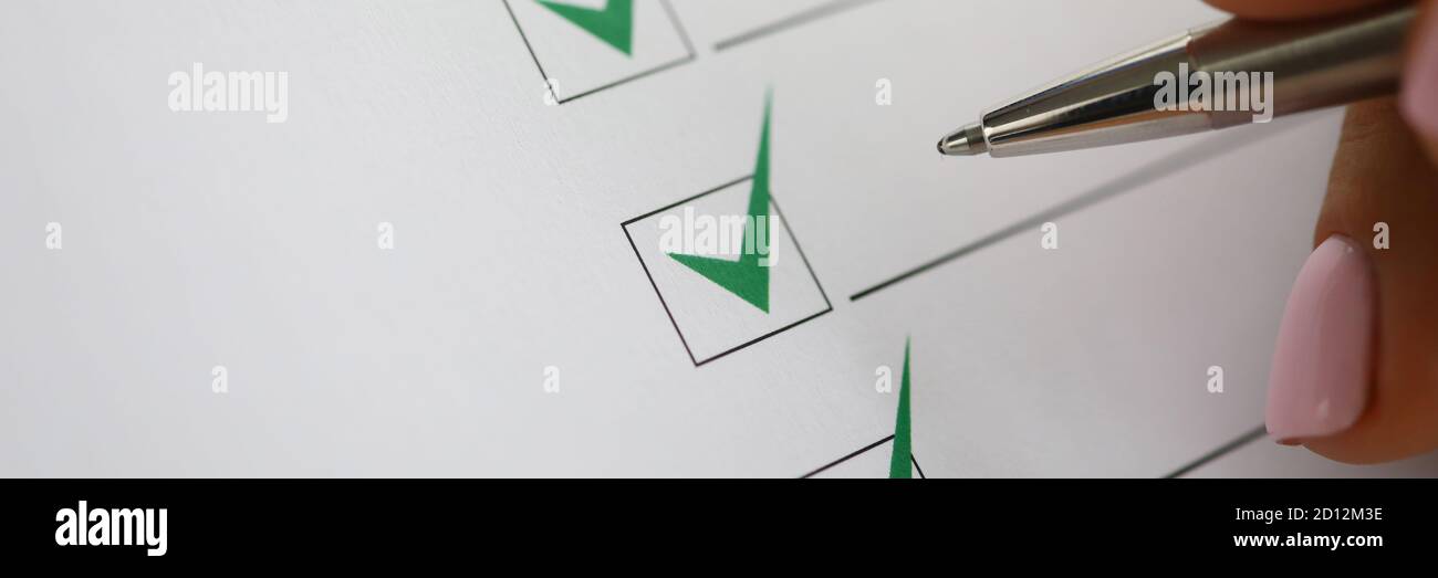 Woman's hand holds pen and marks green check marks in document Stock ...