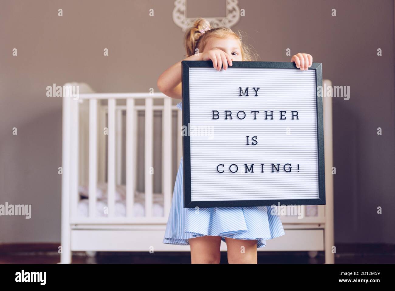 Girl playing in her room with a letter board written my brother is ...