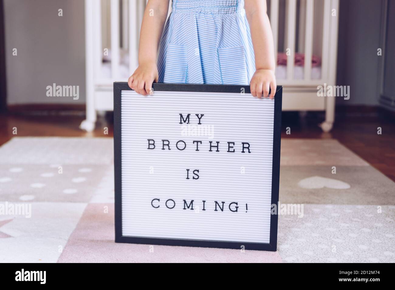 Girl playing in her room with a letter board written my brother is ...