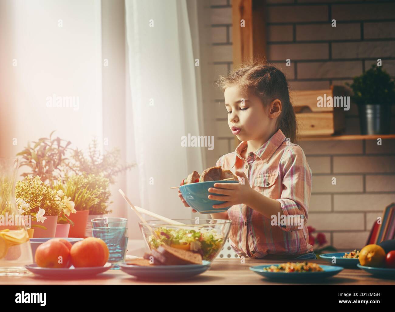 Cute little child girl sets the table for dinner. Healthy food at home ...