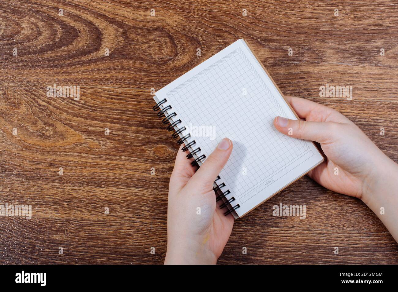 White notebook in hand on a brown color background Stock Photo - Alamy