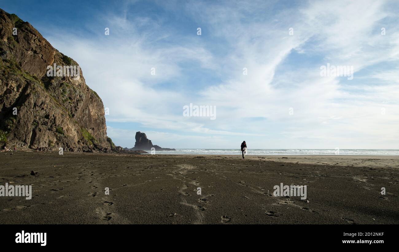 Walking on the black-sand Anawhata beach with keyhole rock in the ...