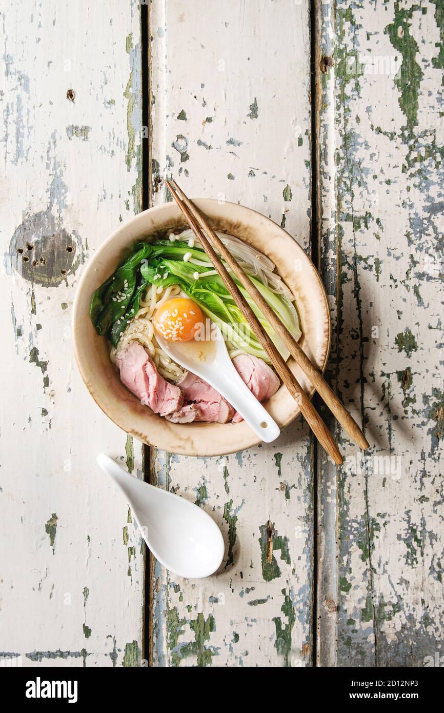 Asian dish udon noodles with egg yolk, sesame, mushrooms, boc choy ...