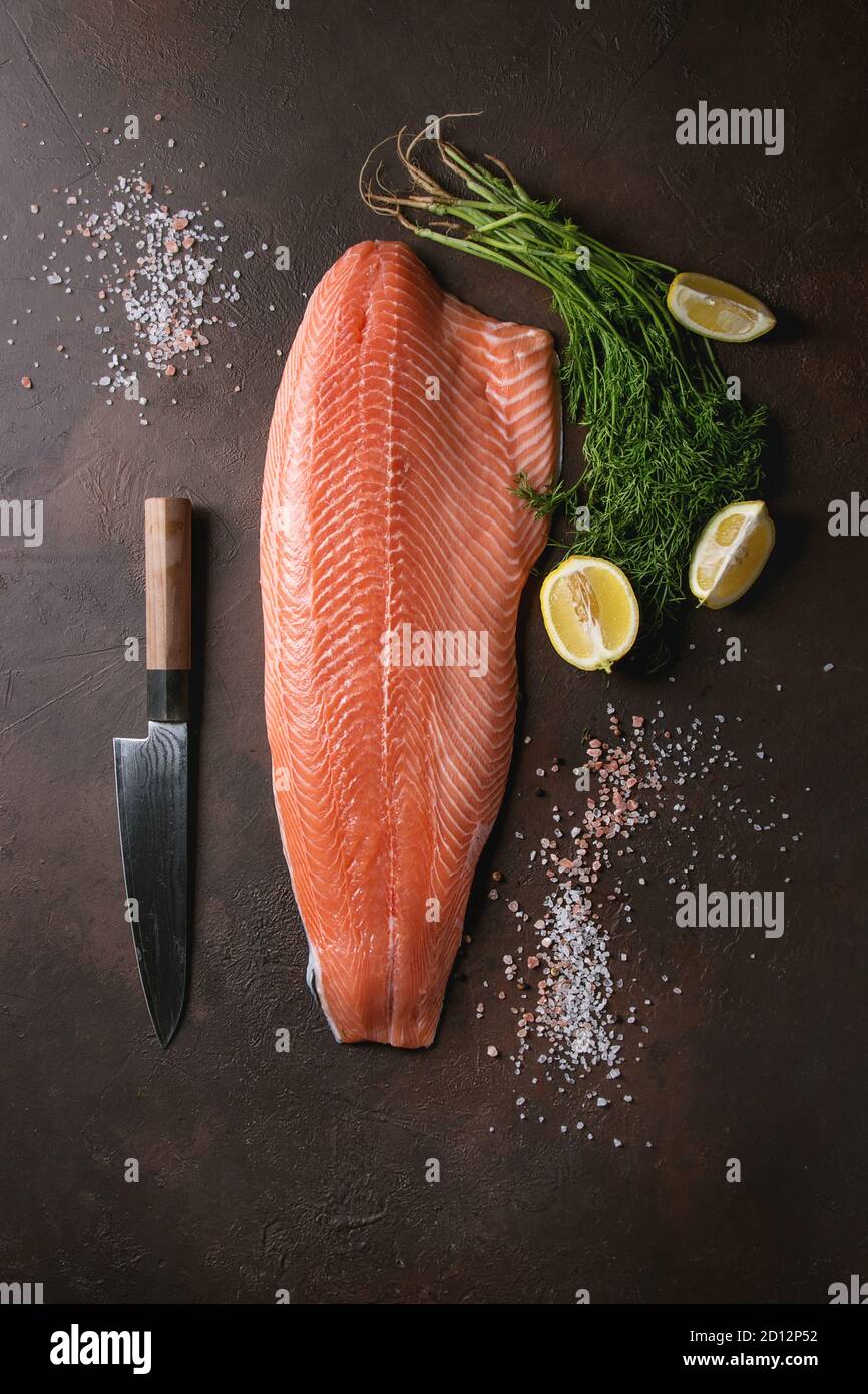 Whole raw uncooked salmon fillet server with green dill, lemon, salt ...