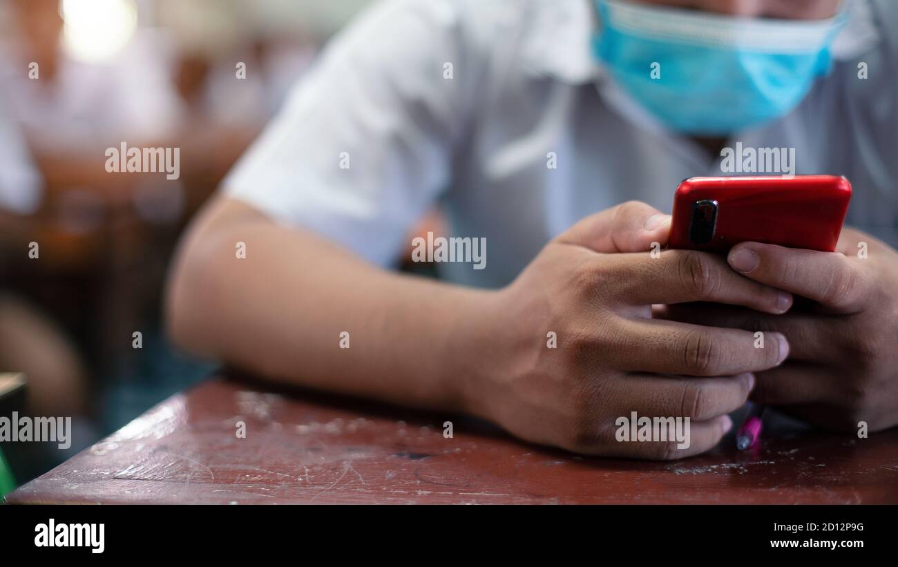 Uniform students are study online or test exam by using smartphone and ...