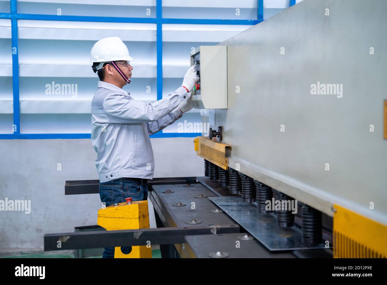 Asian worker wearing a safety suit and setting Hydraulic Press Break ...
