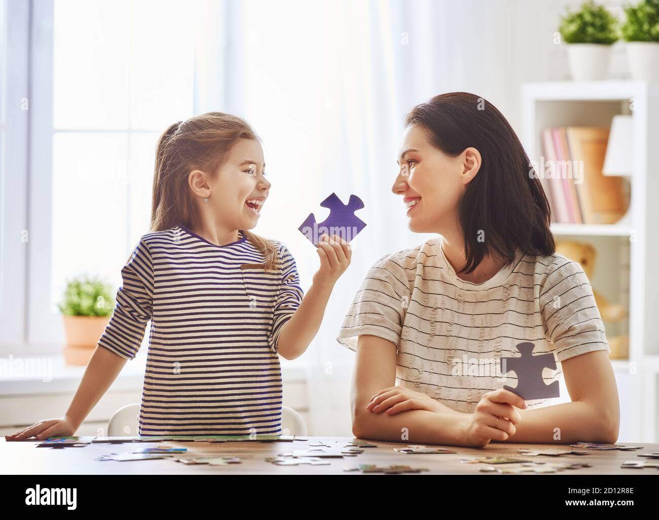 Happy family. Mother and daughter do puzzles together. Adult woman ...