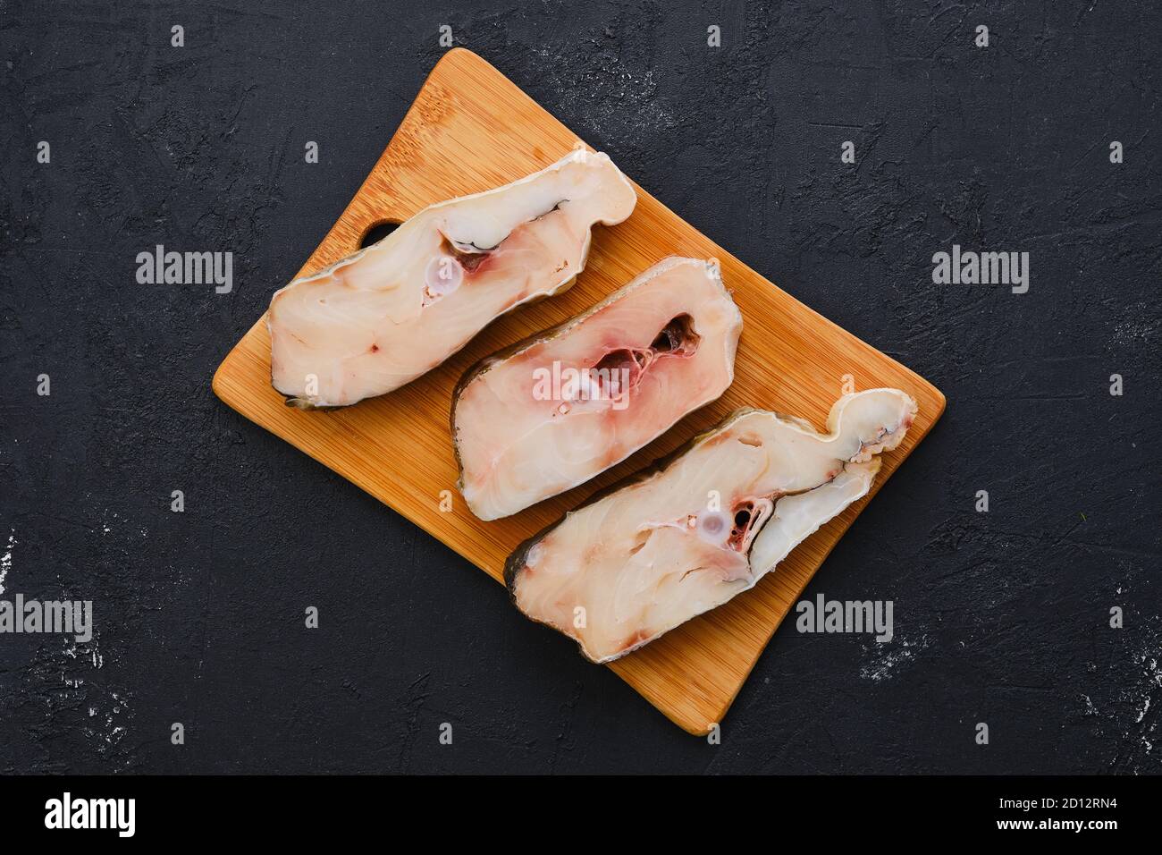 Top view of fresh raw cod steak on wooden cutting board with spice ...