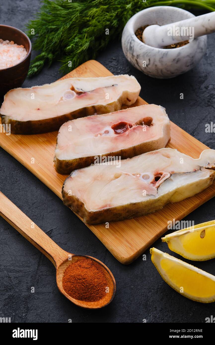 Top view of fresh raw cod steak on wooden cutting board with spice ...