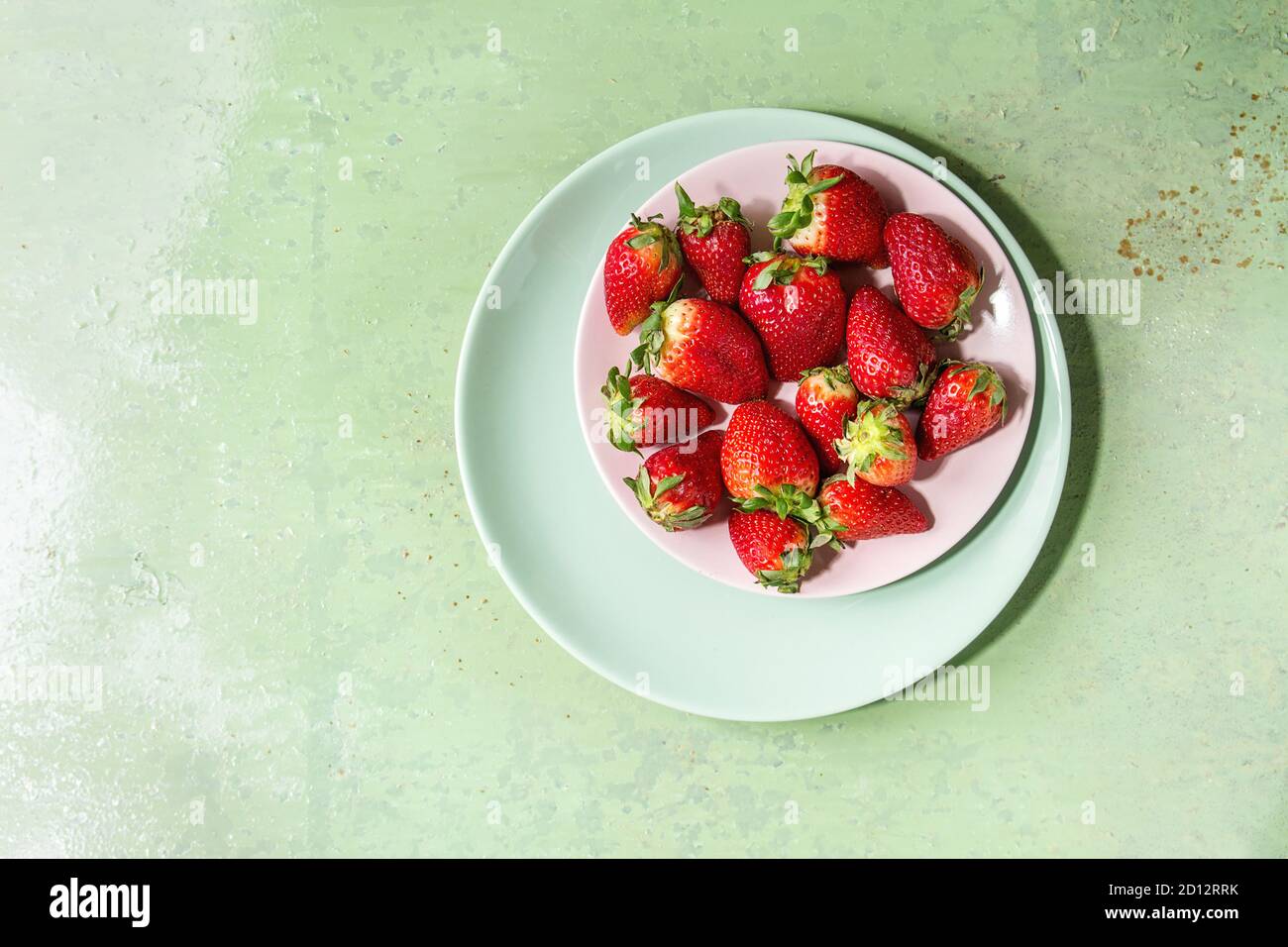 Fresh strawberries on turquoise plate over pink pastel pin-up ...