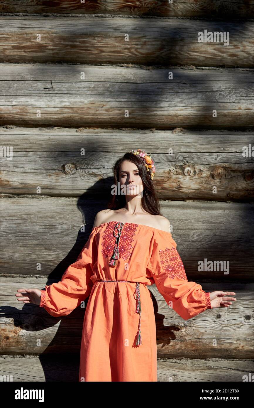 Beautiful Slavic woman in an orange ethnic dress and a wreath of ...