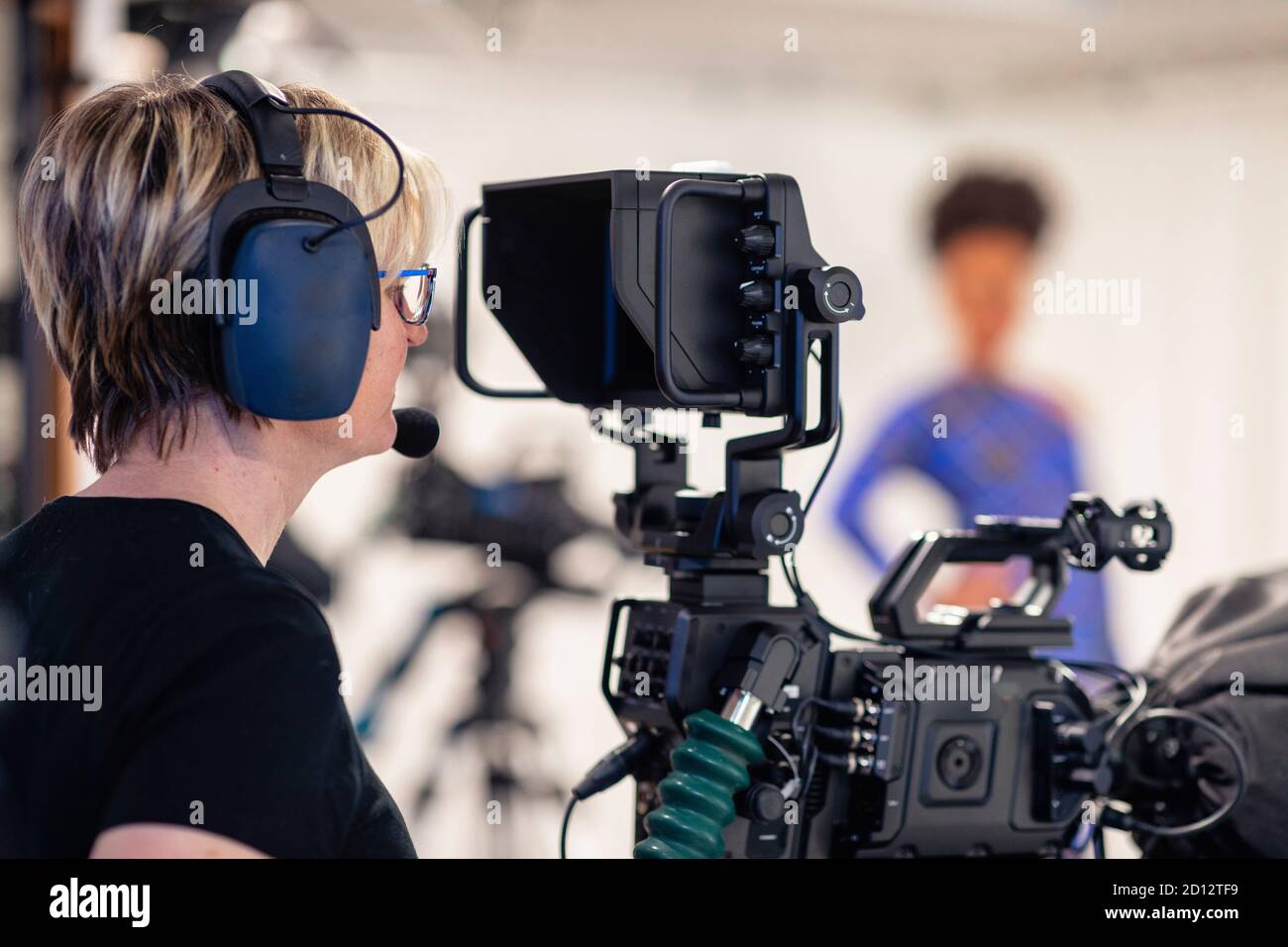 A close-up of a camerawoman, wearing a headset looking through the film ...