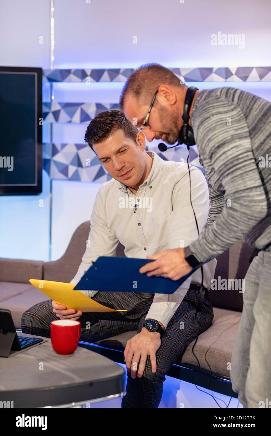 A TV show in the process of being filmed in a studio. The producer is ...