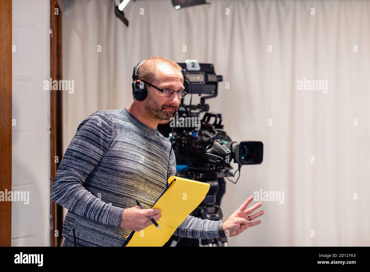 A producer of a TV show, wearing a headset, standing next to a film ...
