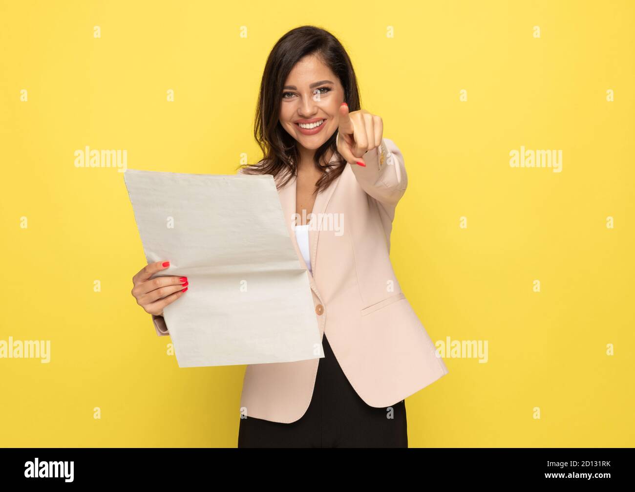 smiling young businesswoman in pink suit smiling, reading newspaper and ...