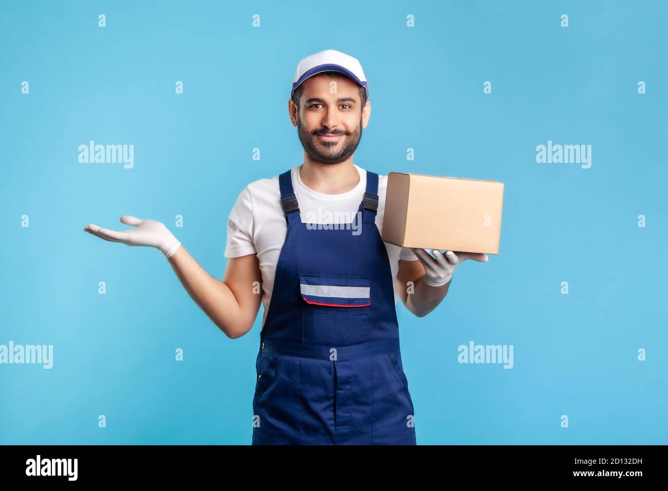 Happy worker in uniform carrying cardboard box and raising other hand ...
