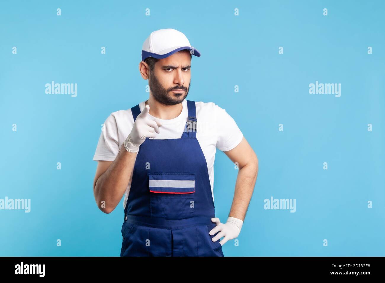 Be careful! Angry handyman in overalls and hygiene gloves standing with ...