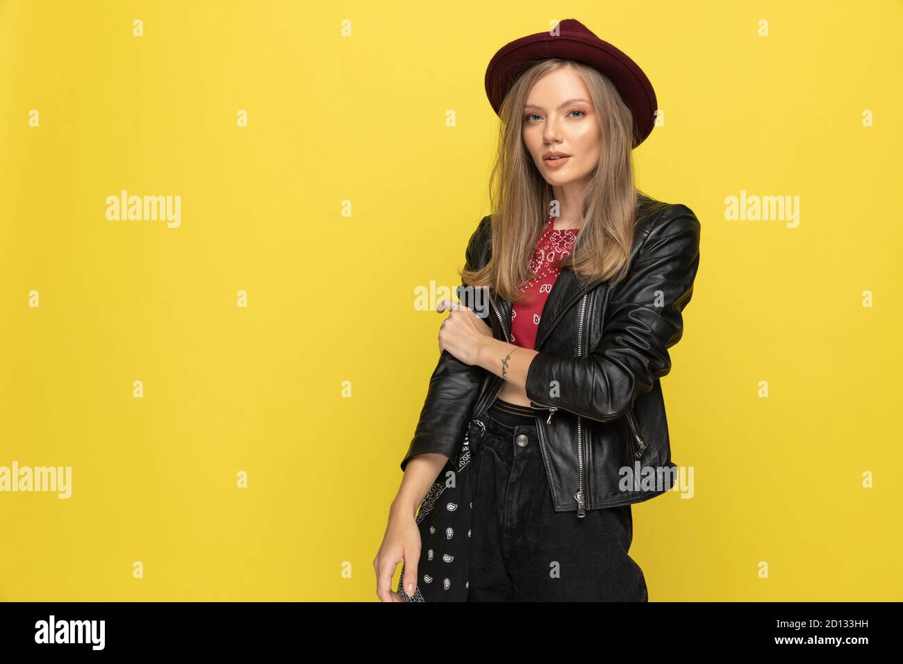 Confident fashion model posing and smiling, standing on yellow studio ...