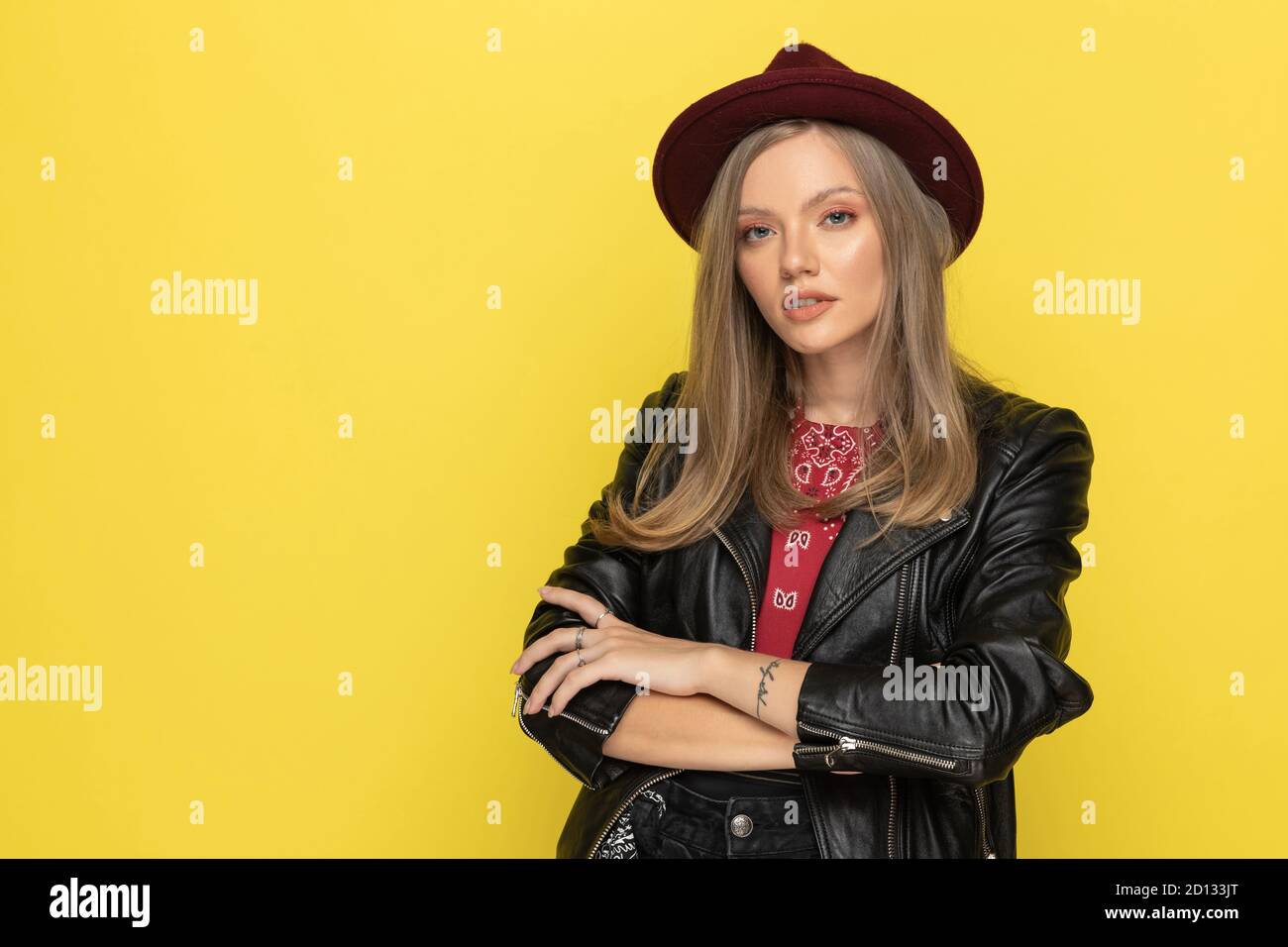 Confident fashion model holding hands folded while wearing hat and ...