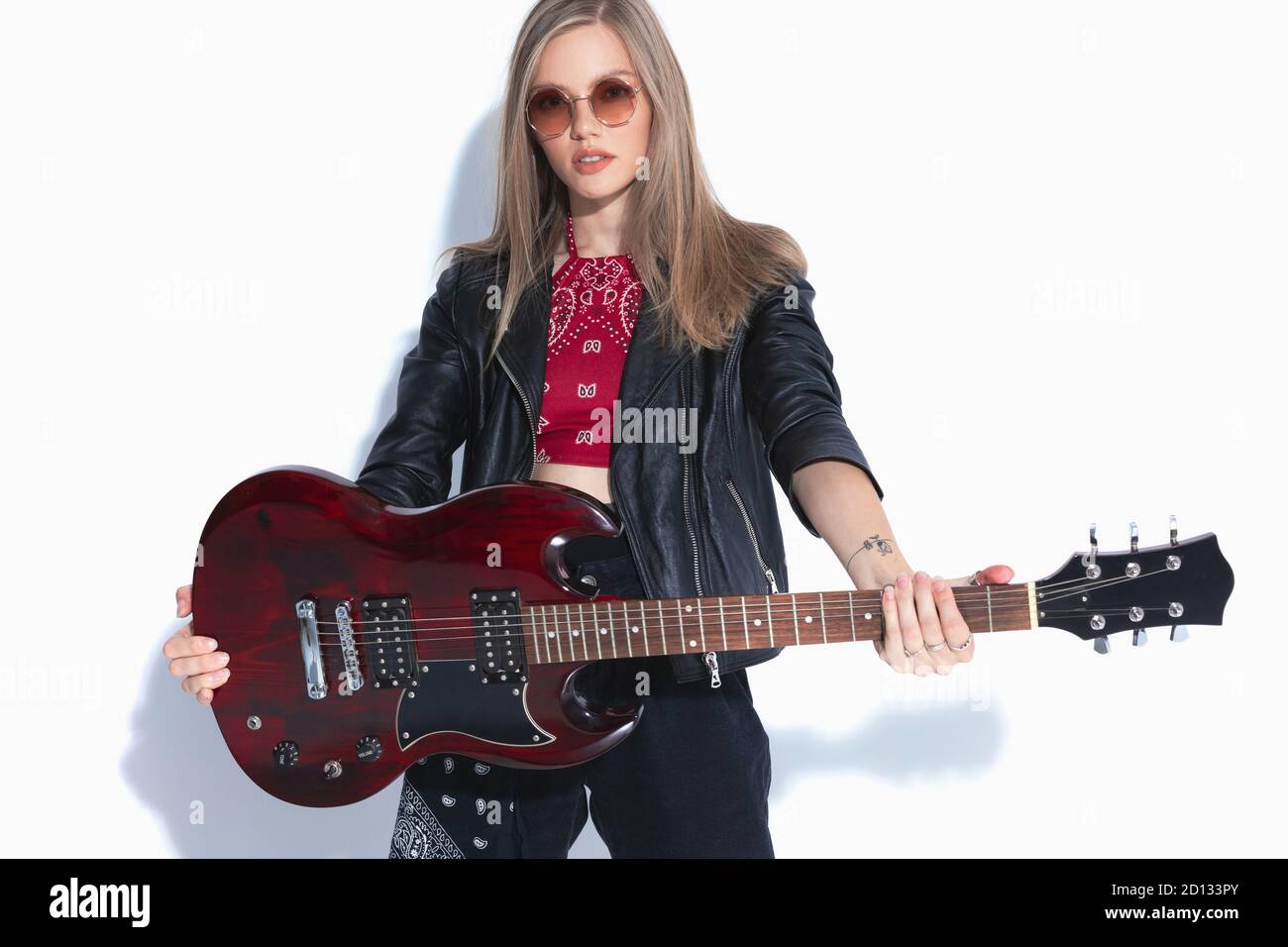 Confident musician woman holding guitar, wearing sunglasses and leather ...