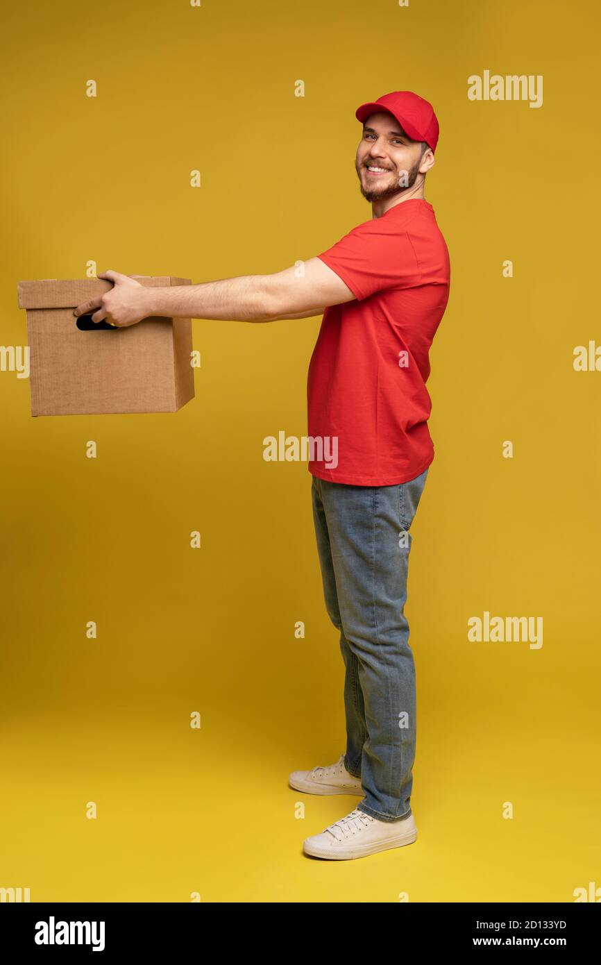 Delivery man with box in studio isolated on yellow background Stock ...