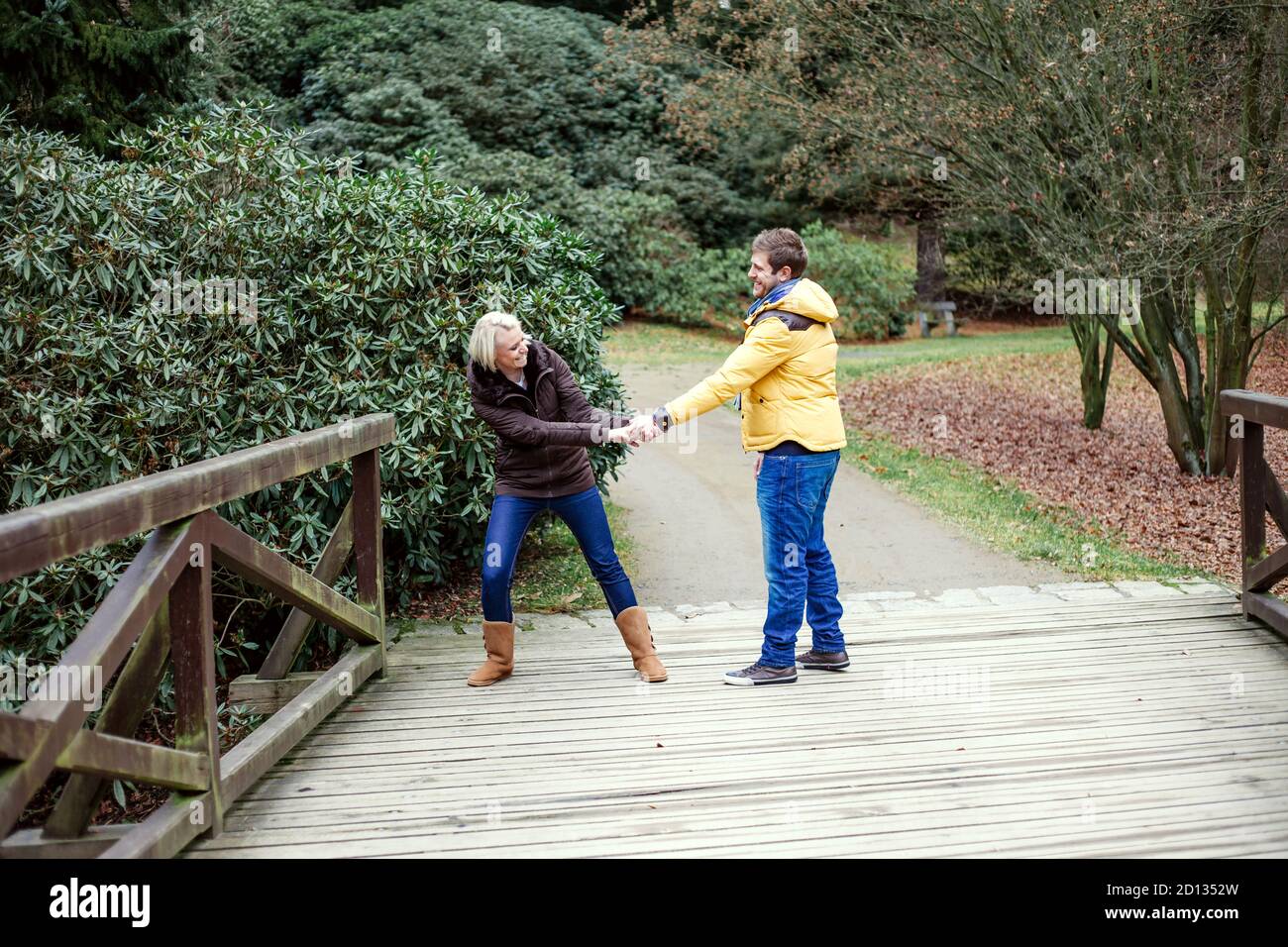 A young couple is fooling around while on a walk in a park. The woman ...