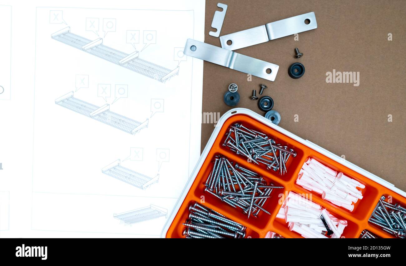 Screws and wall plug in orange plastic box. Top view tool box on brown ...