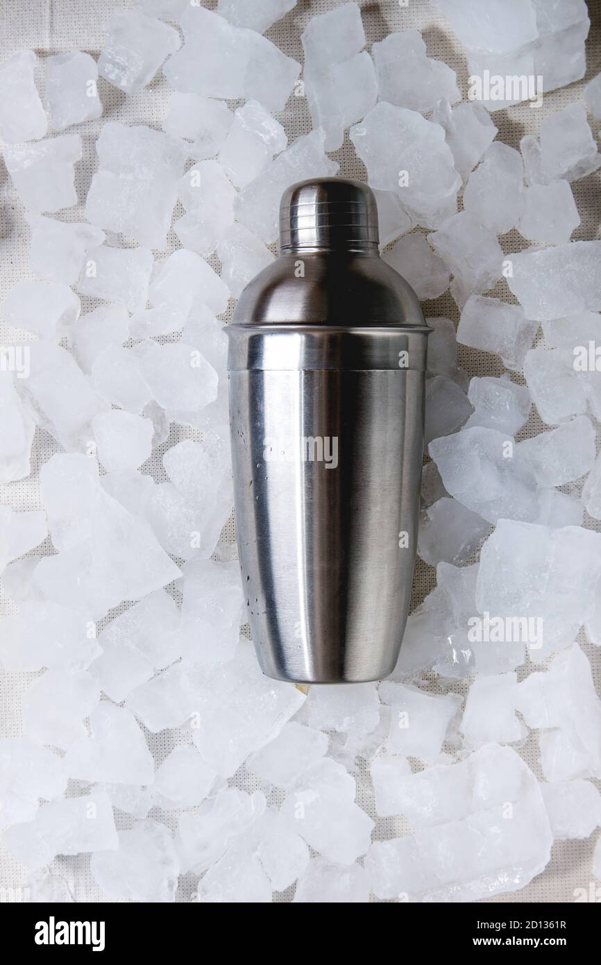 Cocktail making concept. Silver shaker over crushed ice cubes. Flat lay ...