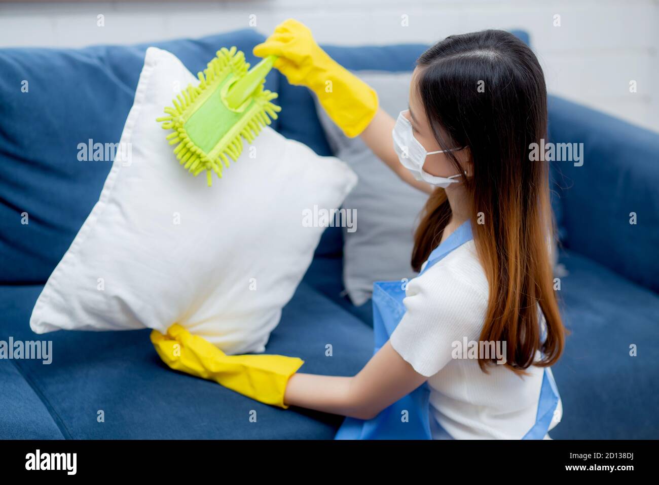 Young asian woman in face mask and gloves cleaning dust with duster on ...