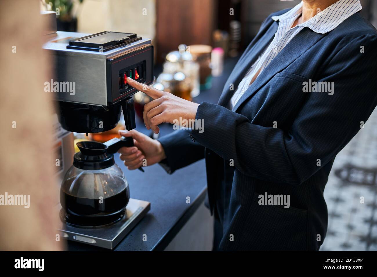 Kind female person doing coffee for guests Stock Photo - Alamy