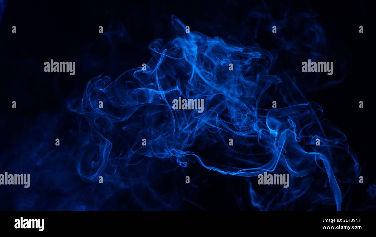 Conceptual image of blue color smoke isolated on dark black background ...
