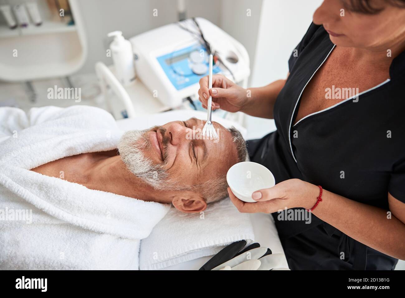 Skillful cosmetology specialist putting lotion on face of a man Stock ...