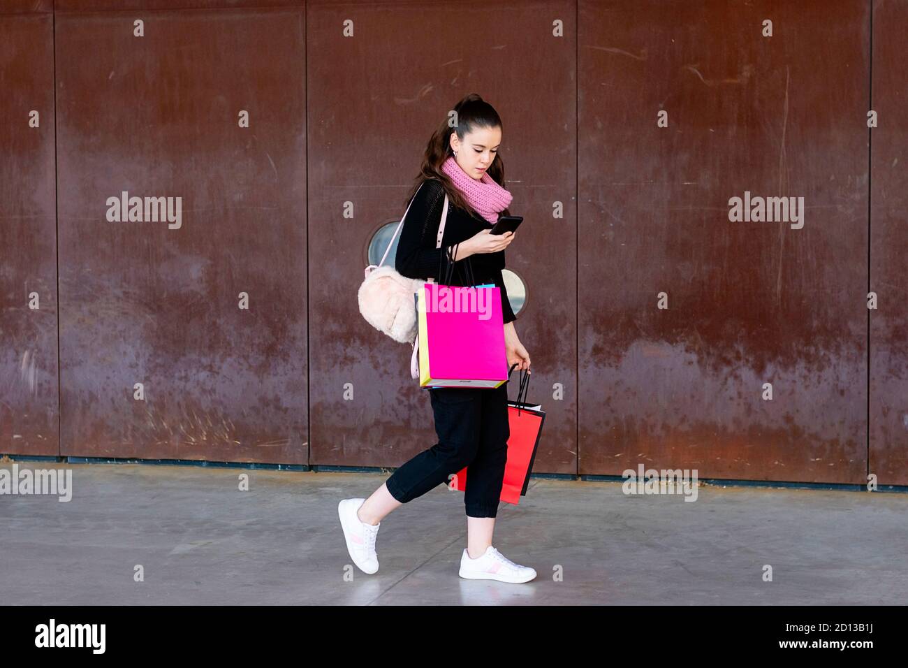 Woman walking with shopping bags and cellphone Stock Photo - Alamy
