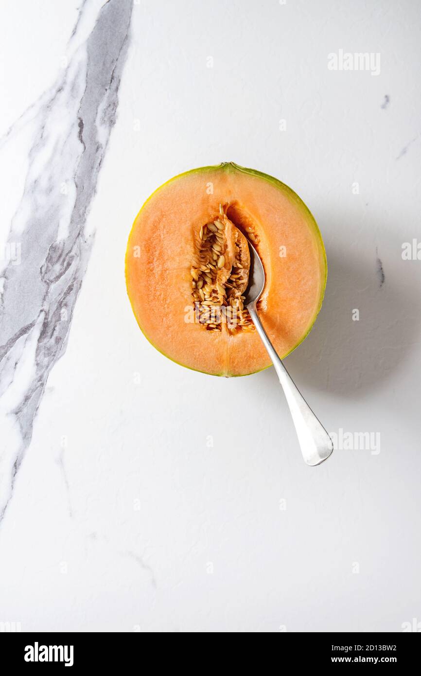 Half of ripe organic Cantaloupe melon with seeds and spoon inside over ...