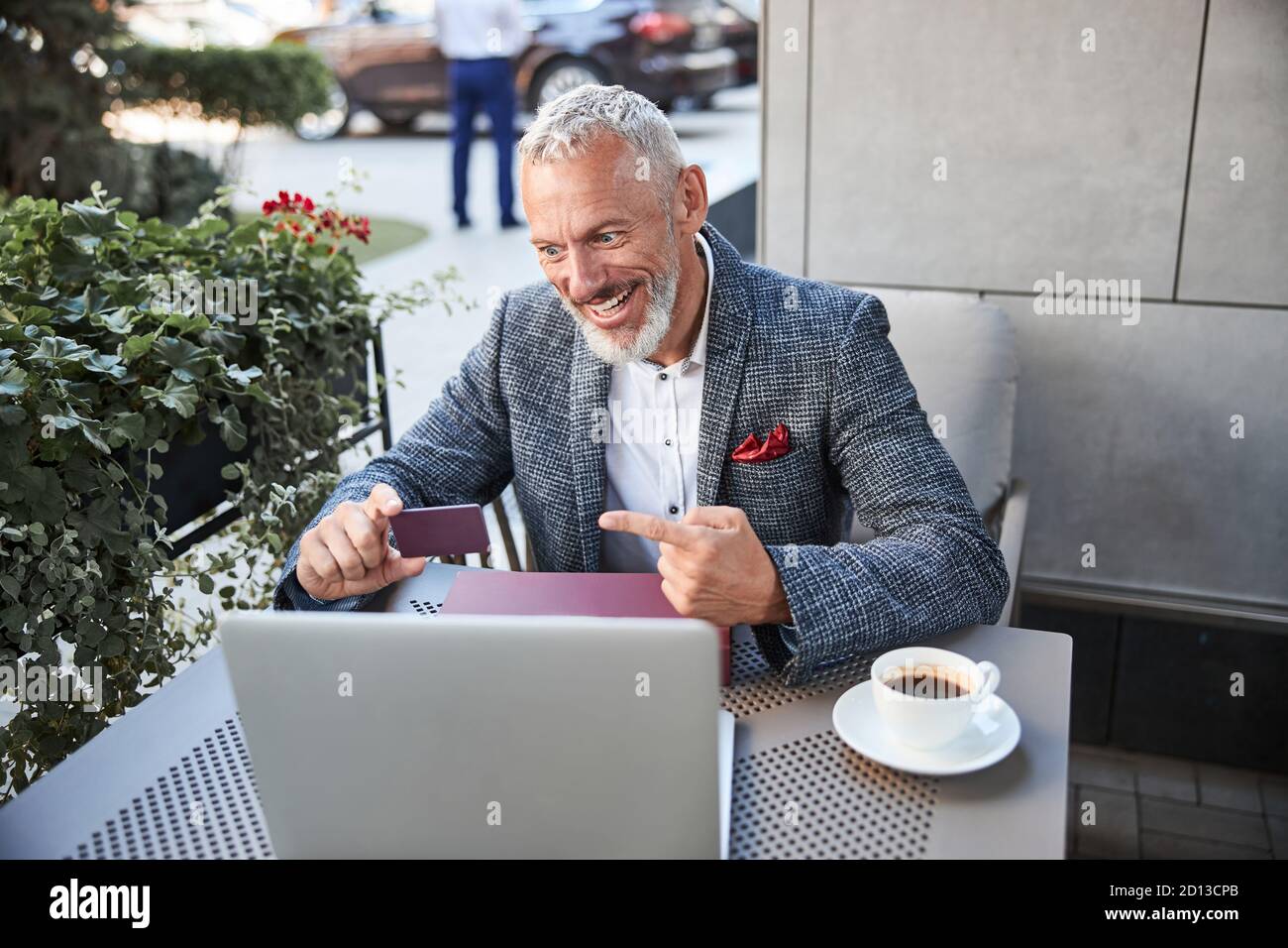 Energetic grey-haired man making a video-call and showing a card Stock ...
