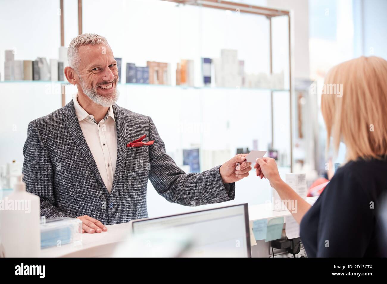 Contented man taking a card from a shop staffmember Stock Photo - Alamy