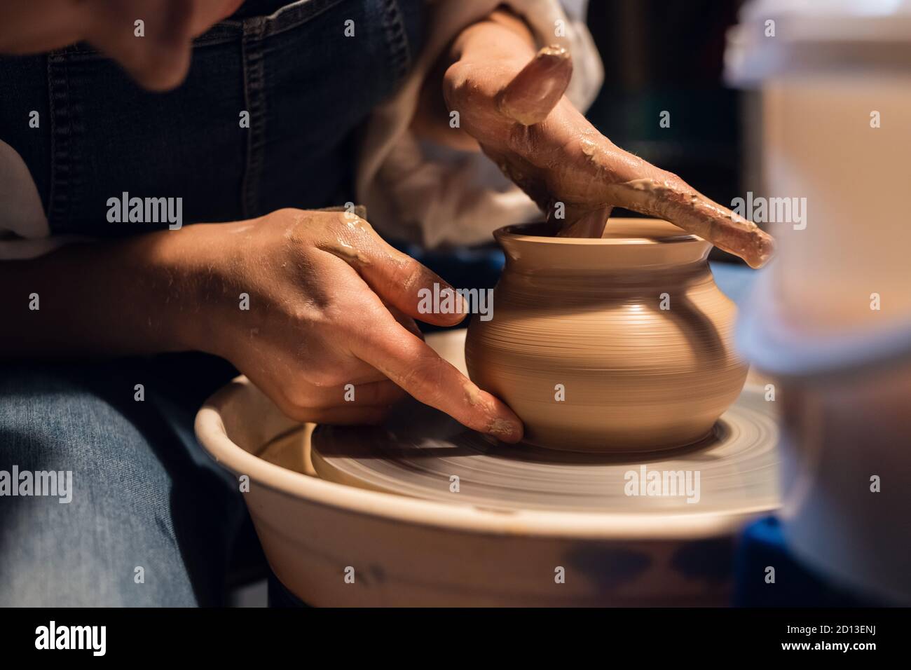 a master in a pottery workshop shows the technique of modeling a pot on ...