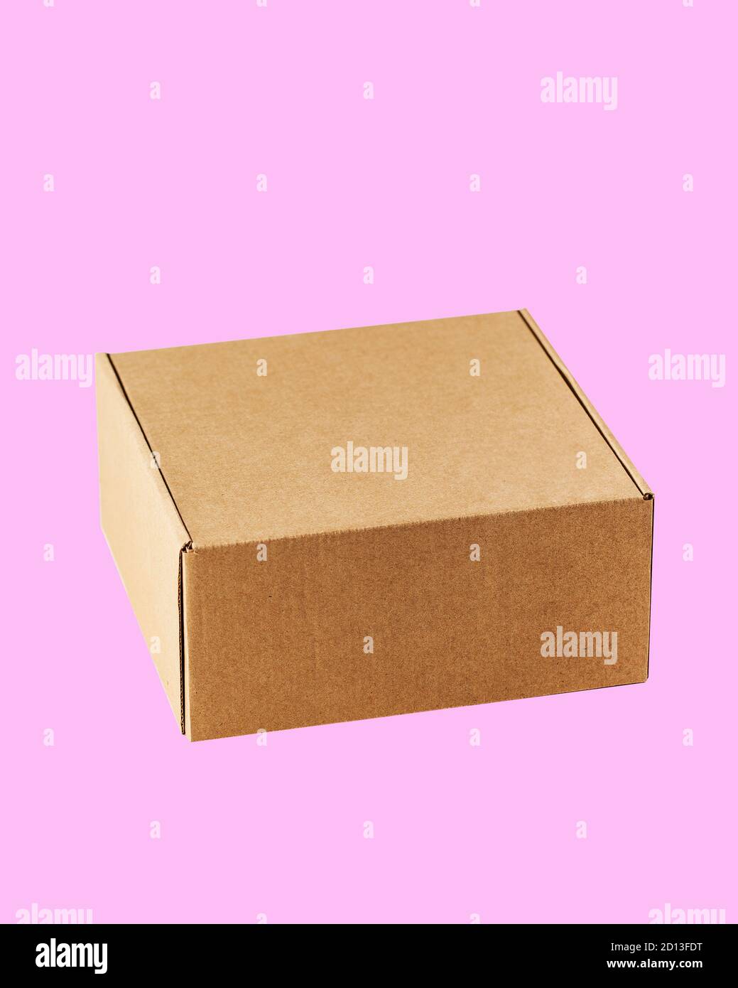 Kraft cardboard square closed box. The box is carved on a pink ...