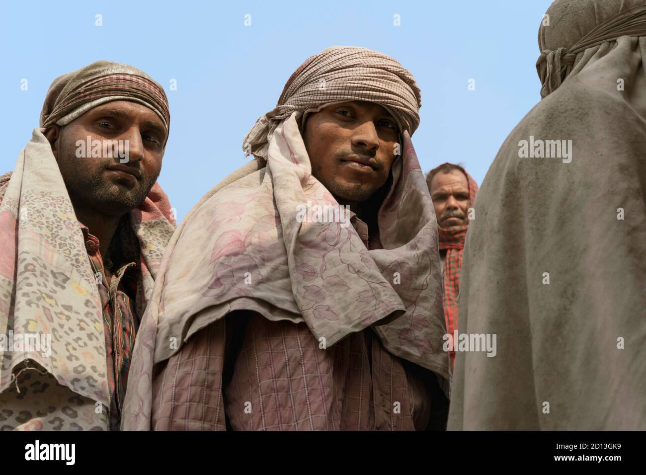 Workers employed to move heavy bags of cement queue to collect their ...
