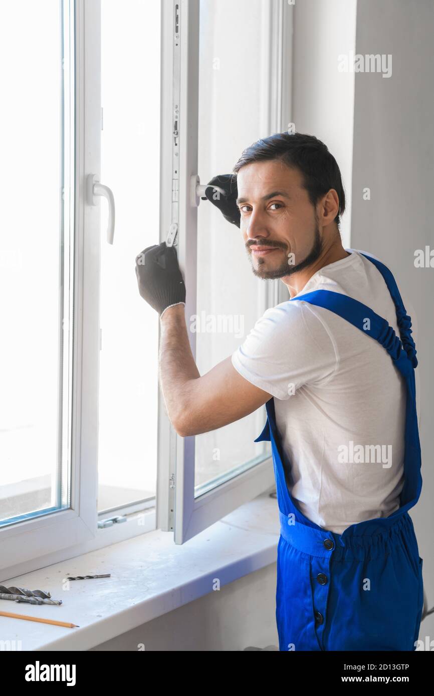 Handyman in work clothes preparing to install a window Stock Photo - Alamy