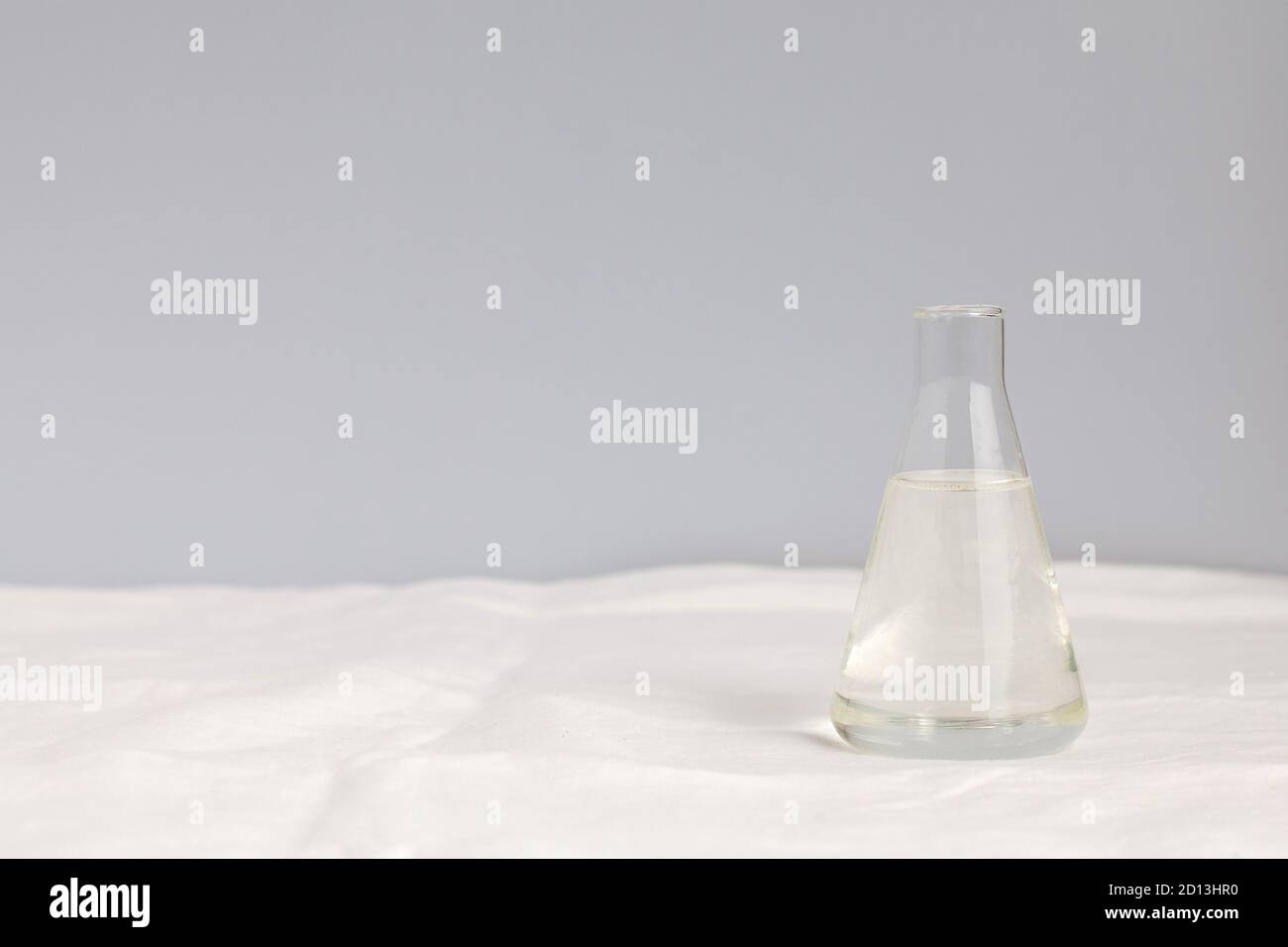 Glass transparent flask with water on a white and a blue background ...