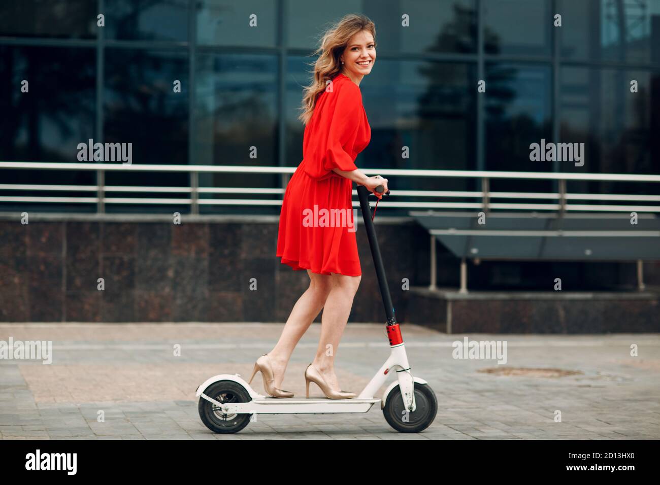 Young Adult Perfect Woman Riding Electric Scooter In Red Dress At The