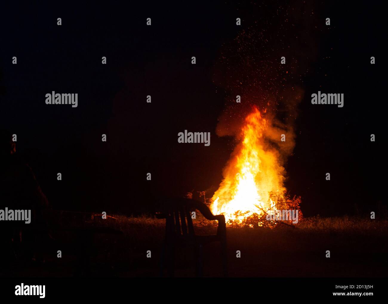 Beautiful big bonfire in the forest at night. A man looks at a bonfire ...