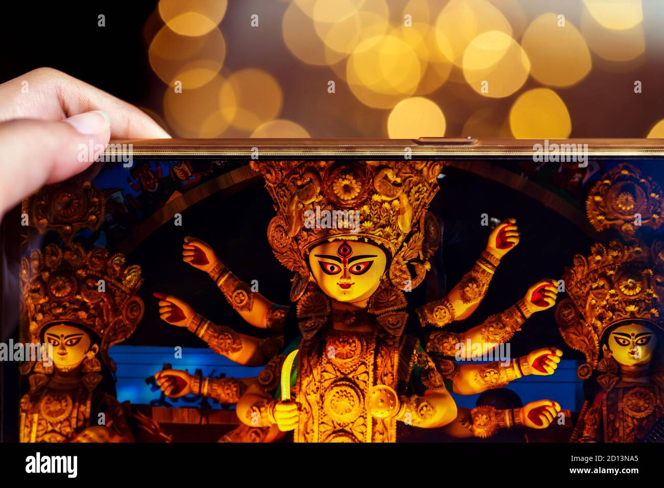 Hand holding mobile phone and taking photos of Goddess Durga idol at a ...