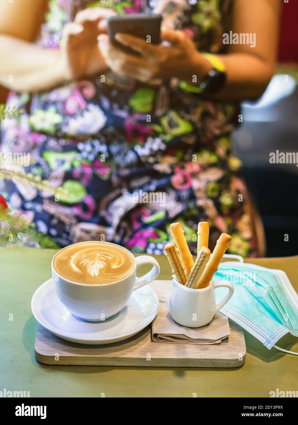 Hot Cappuccino coffee with protective mask on a wooden table for people ...
