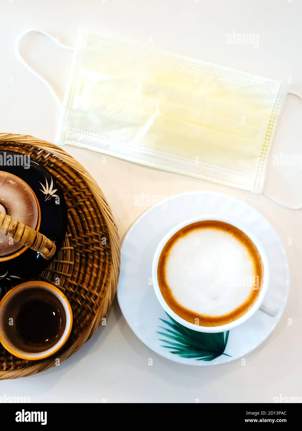 Hot Cappuccino coffee with protective mask on a wooden table for people ...