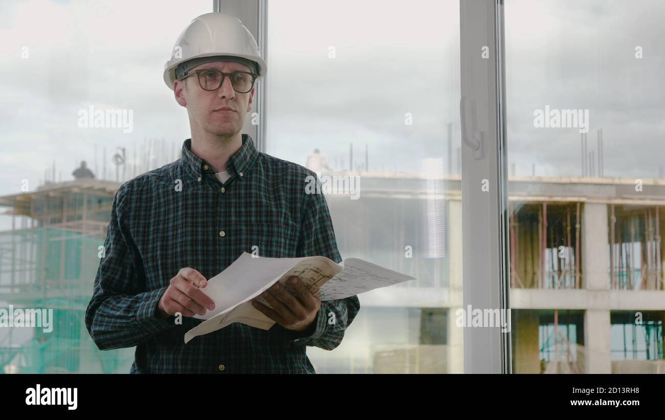 Construction engineer looking at blueprint and the room in front of him ...