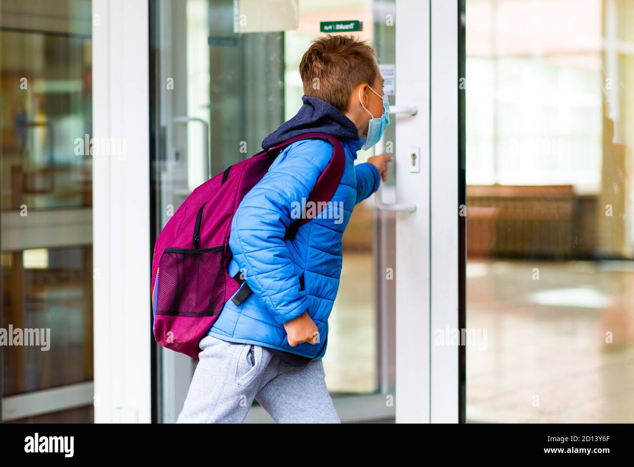 Back view of 9s boy wearing protective mask is trying to open the ...