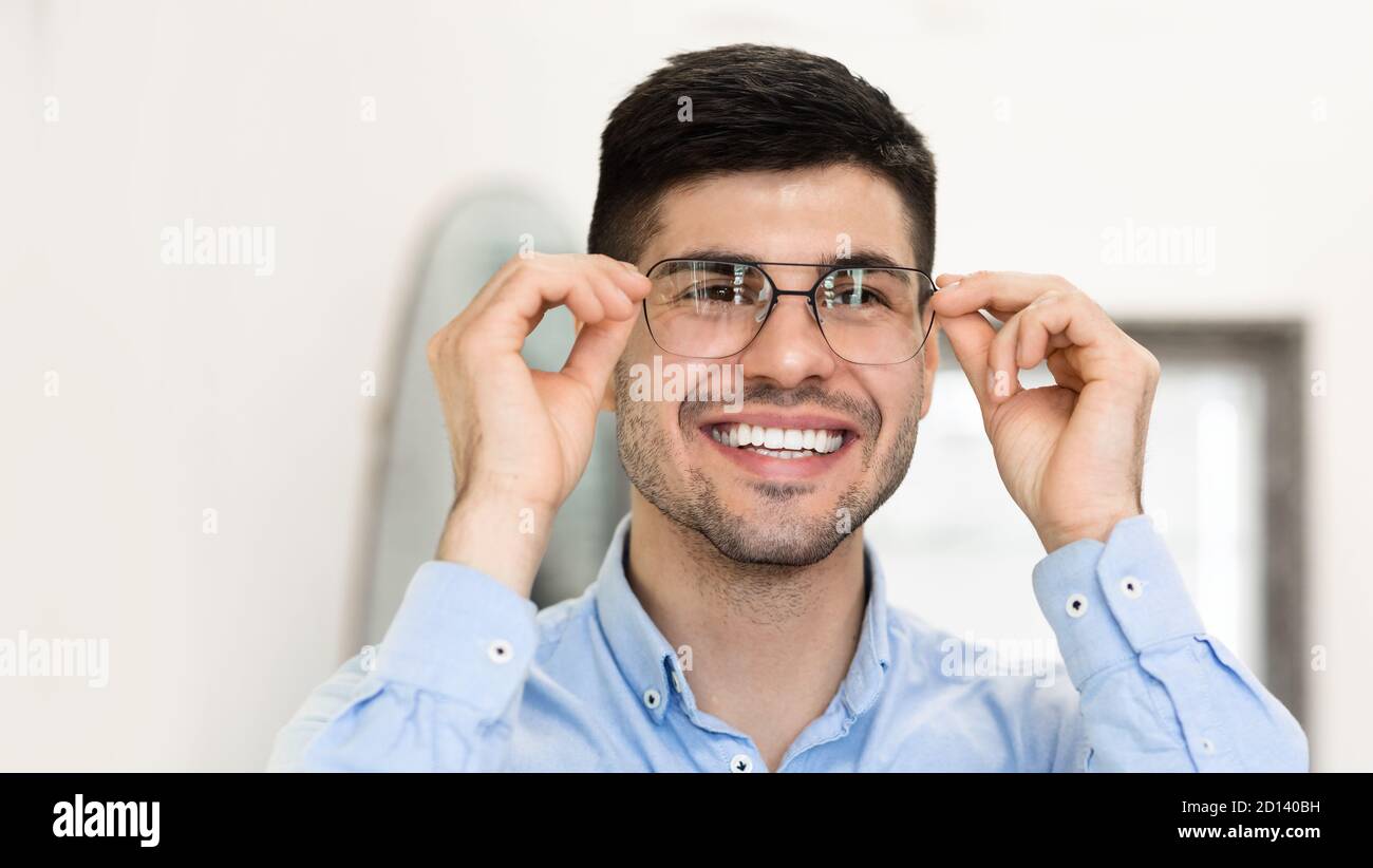 Portrait of smiling handsome man trying on spectacles Stock Photo - Alamy