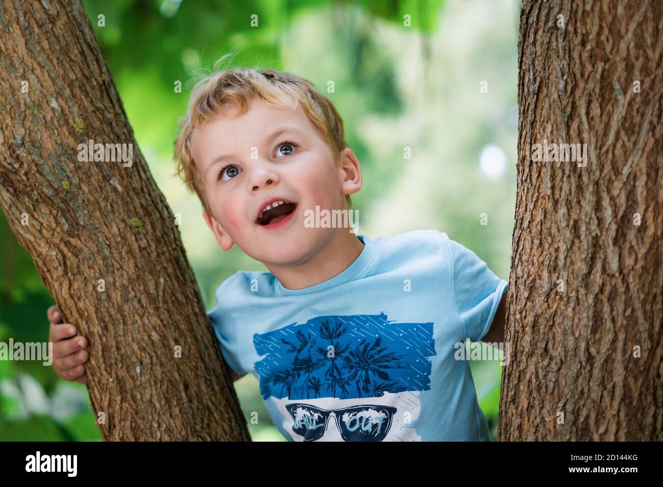 Little child standing next to tree Stock Photo - Alamy
